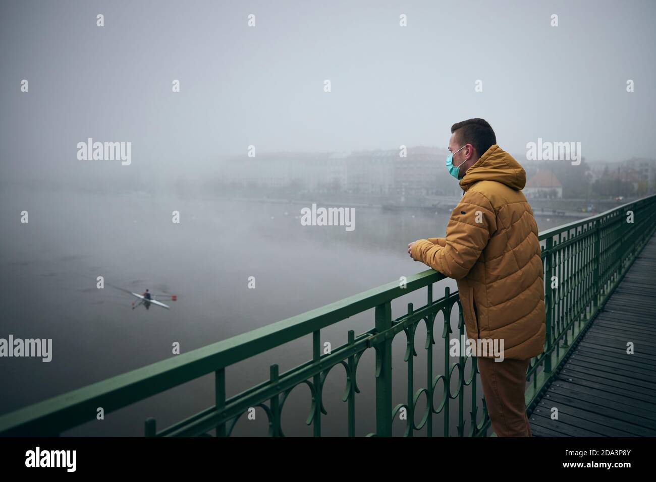 Lonely man wearing face mask on bridge against city in fog. Themes life ...