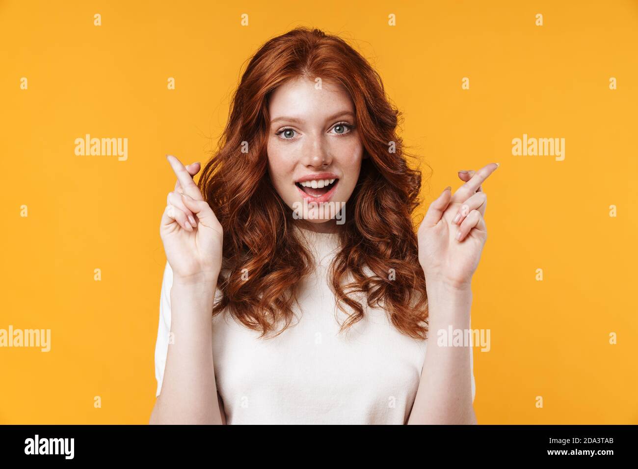 Image of ginger surprised girl holding fingers crossed for good luck ...