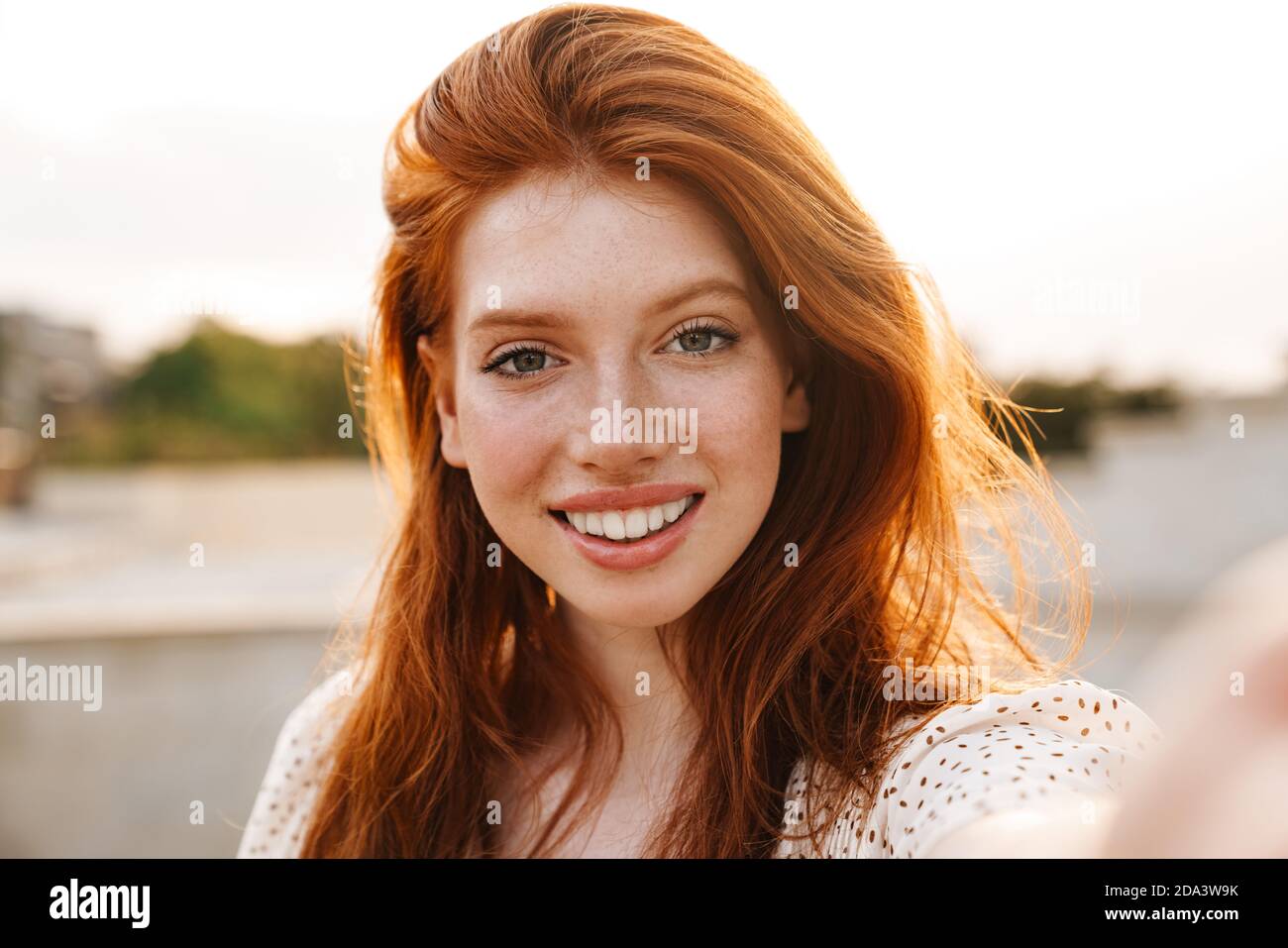 Image of cheerful ginger girl taking selfie and smiling at camera at ...