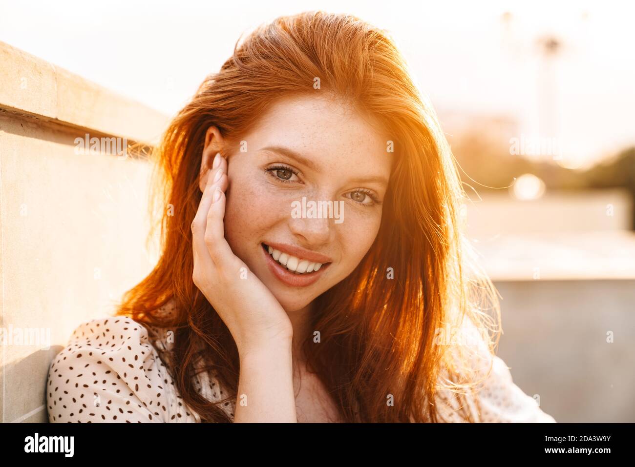 Image of cheerful ginger girl smiling and looking at camera at city ...