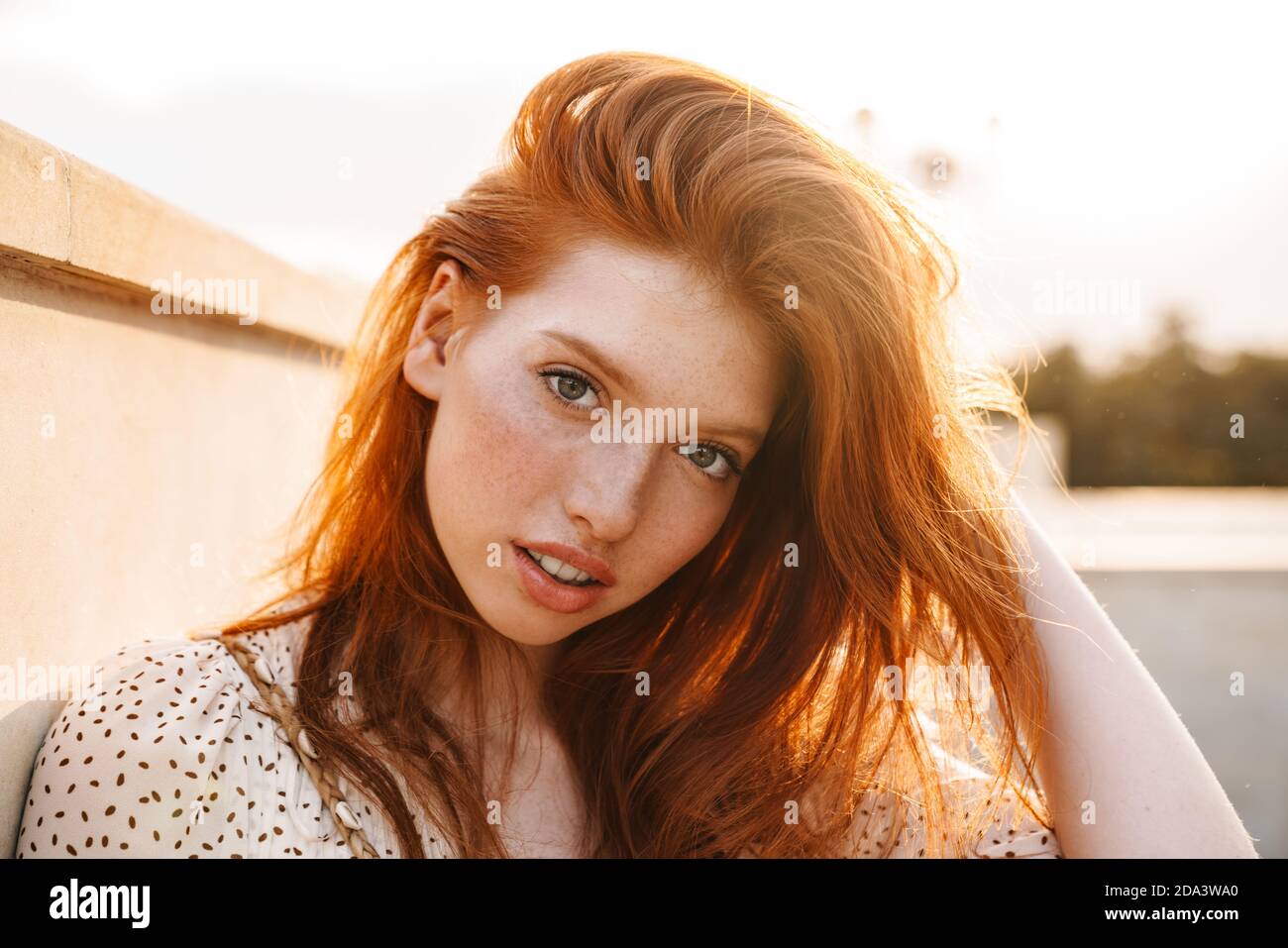 Image of pleased ginger girl posing and looking at camera at city ...