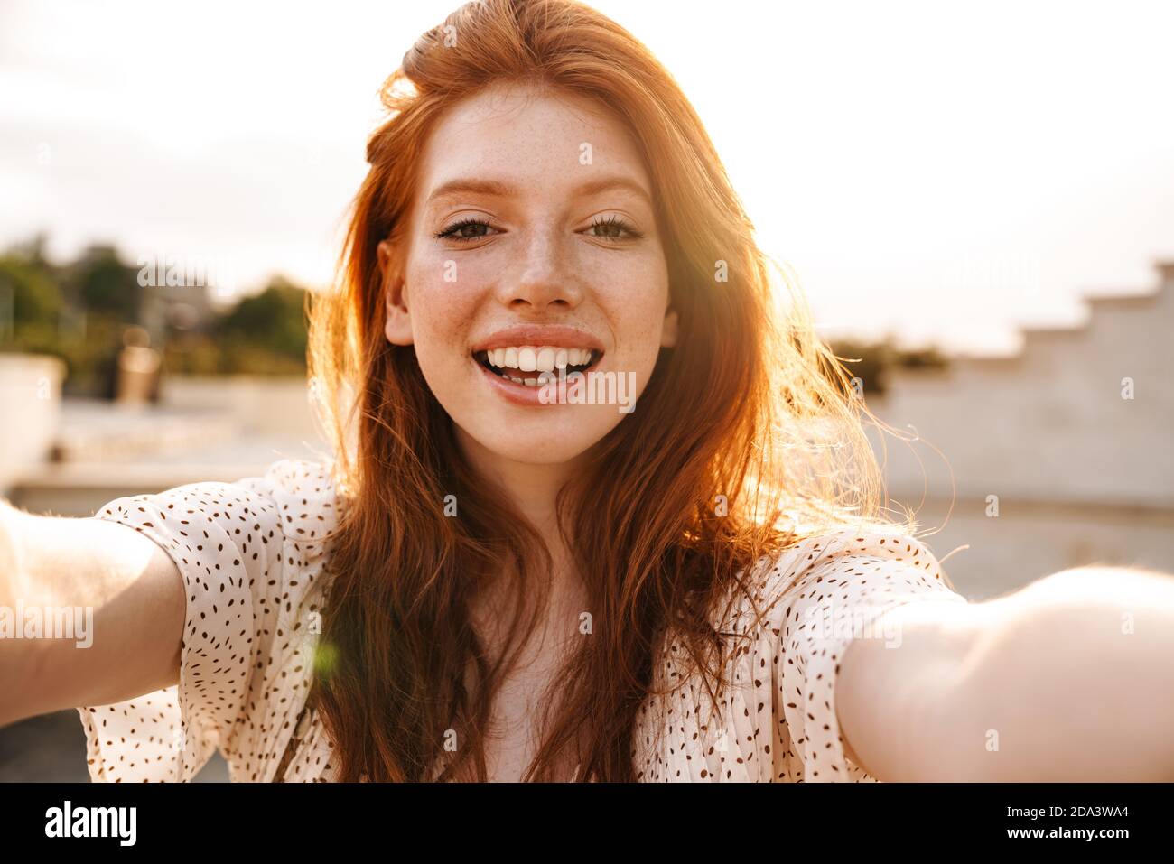 Image of cheerful ginger girl taking selfie and smiling at camera at ...