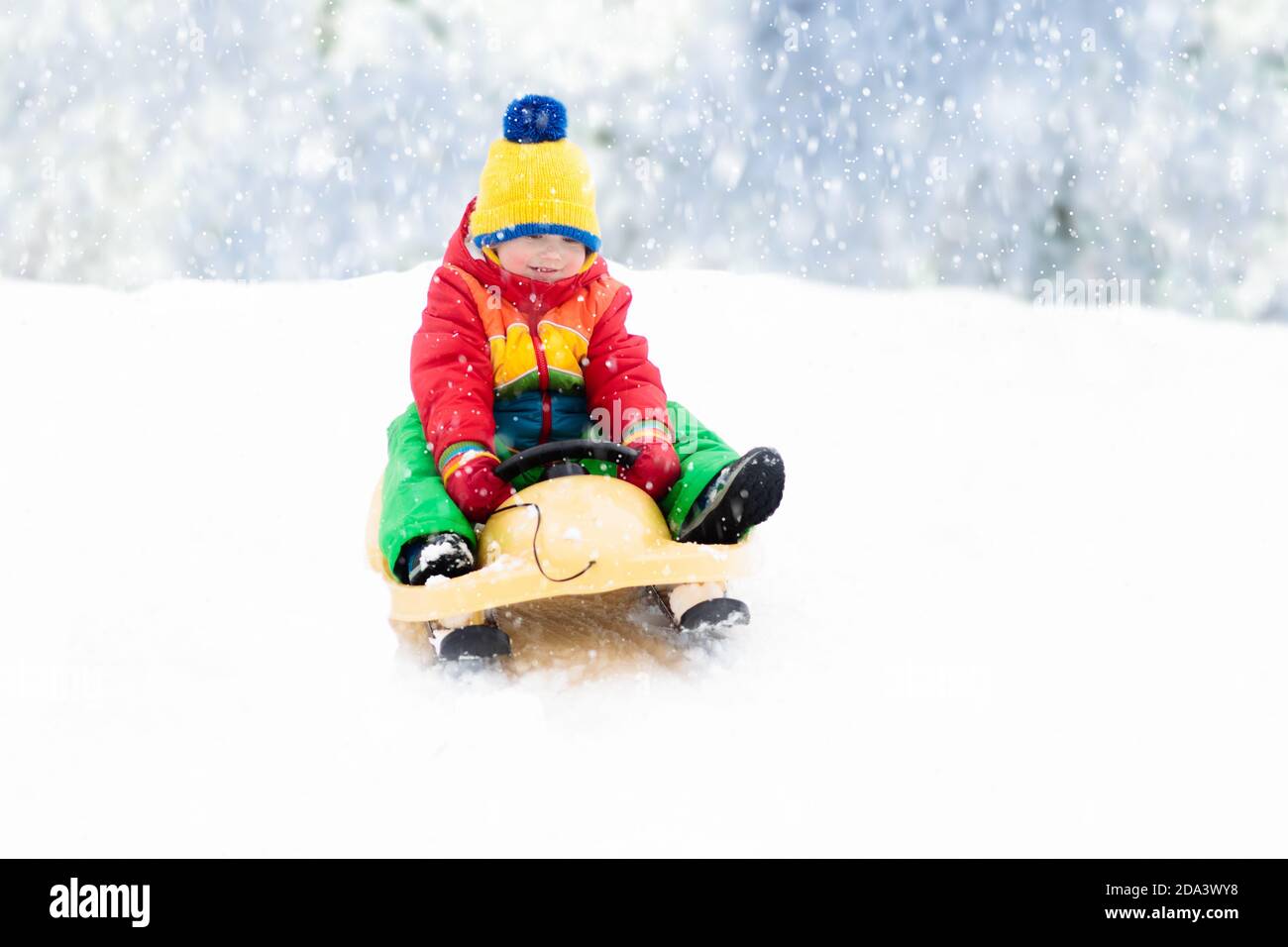 Little boy enjoying a sleigh ride. Child sledding. Toddler kid riding a ...