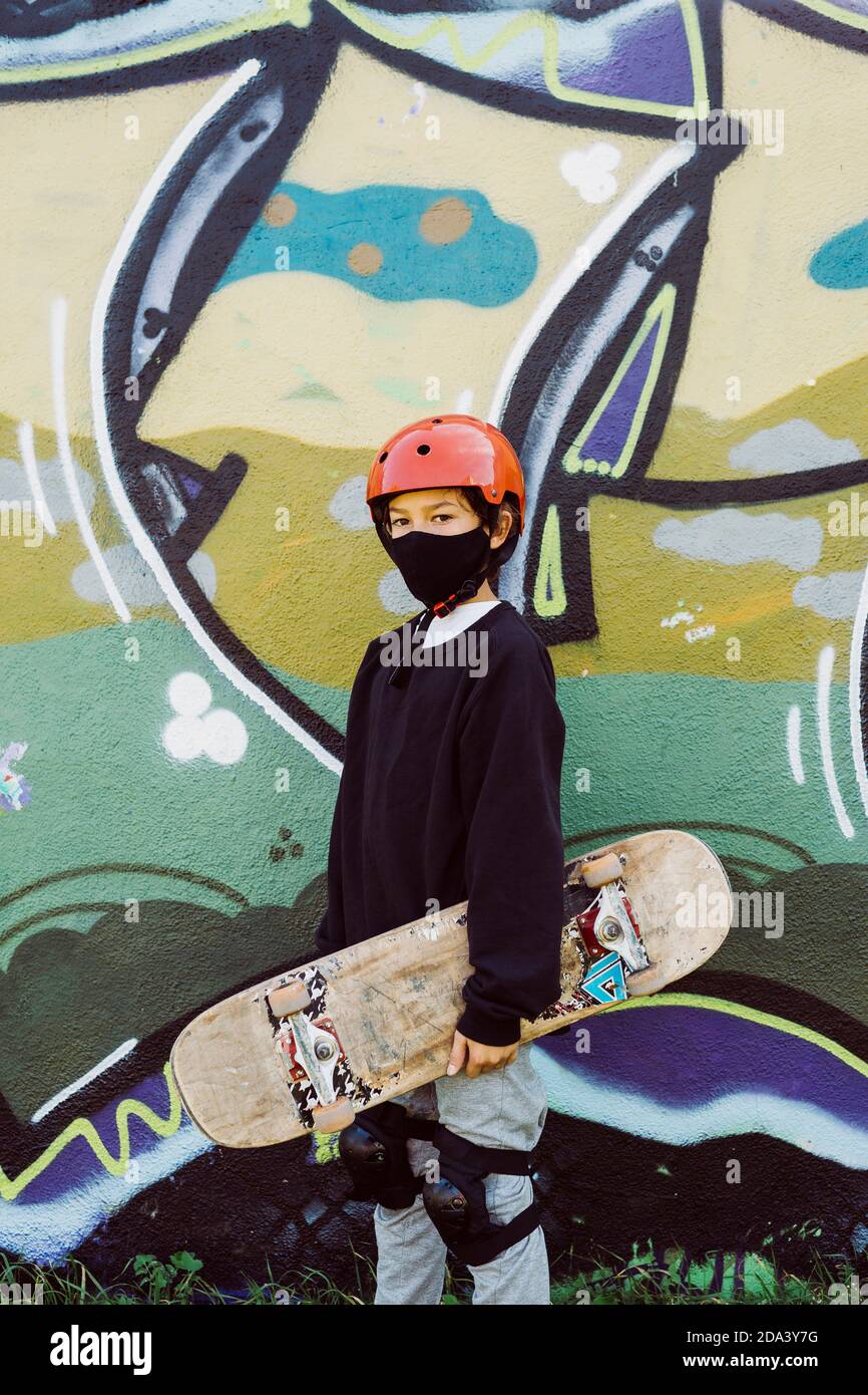 Portrait of a young skater boy with an old skateboard and a red helmet ...