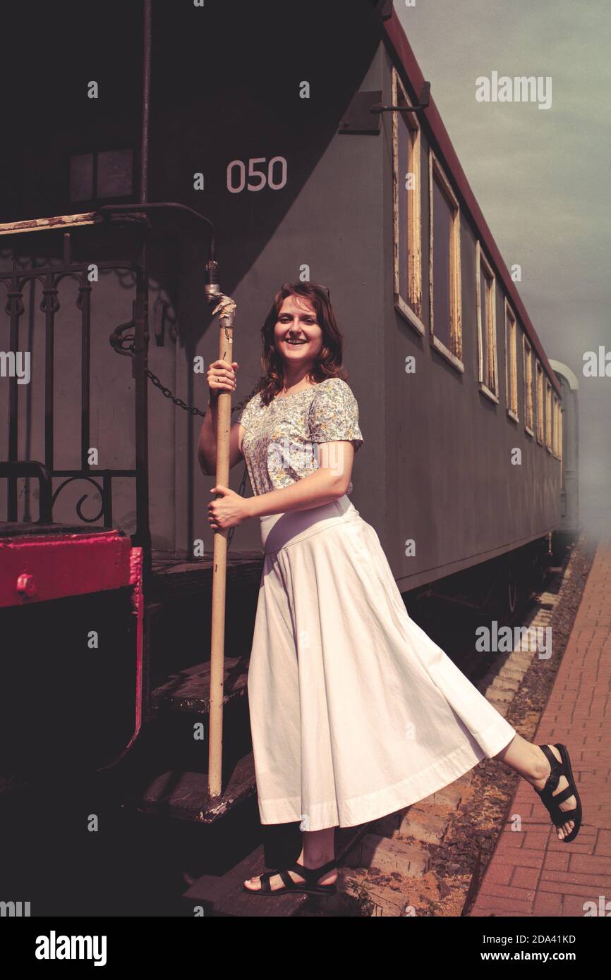 A girl stands on the steps of the cars train. Vintage train is at the ...