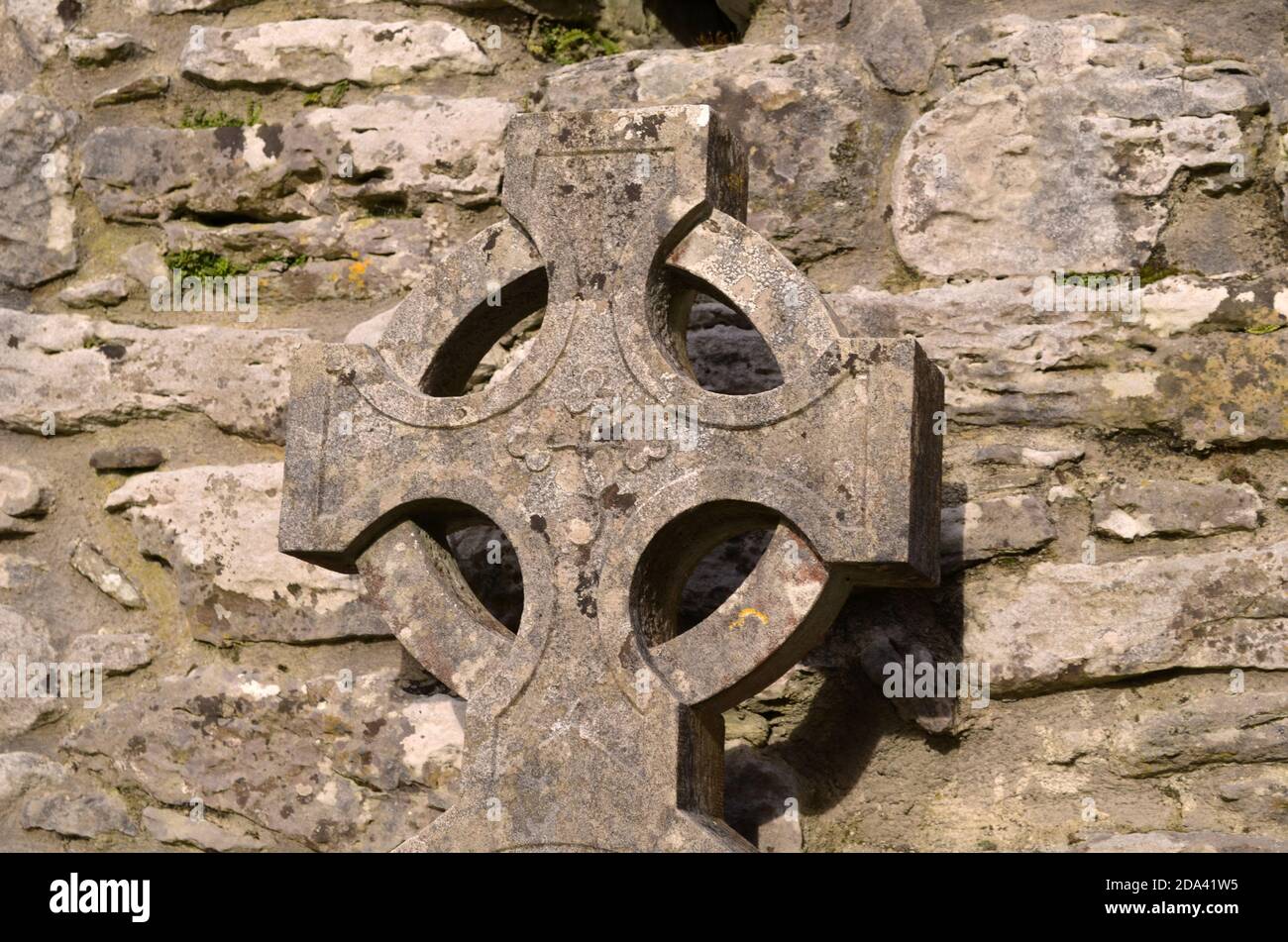 Irish celtic cross in front of a stone wall Stock Photo - Alamy