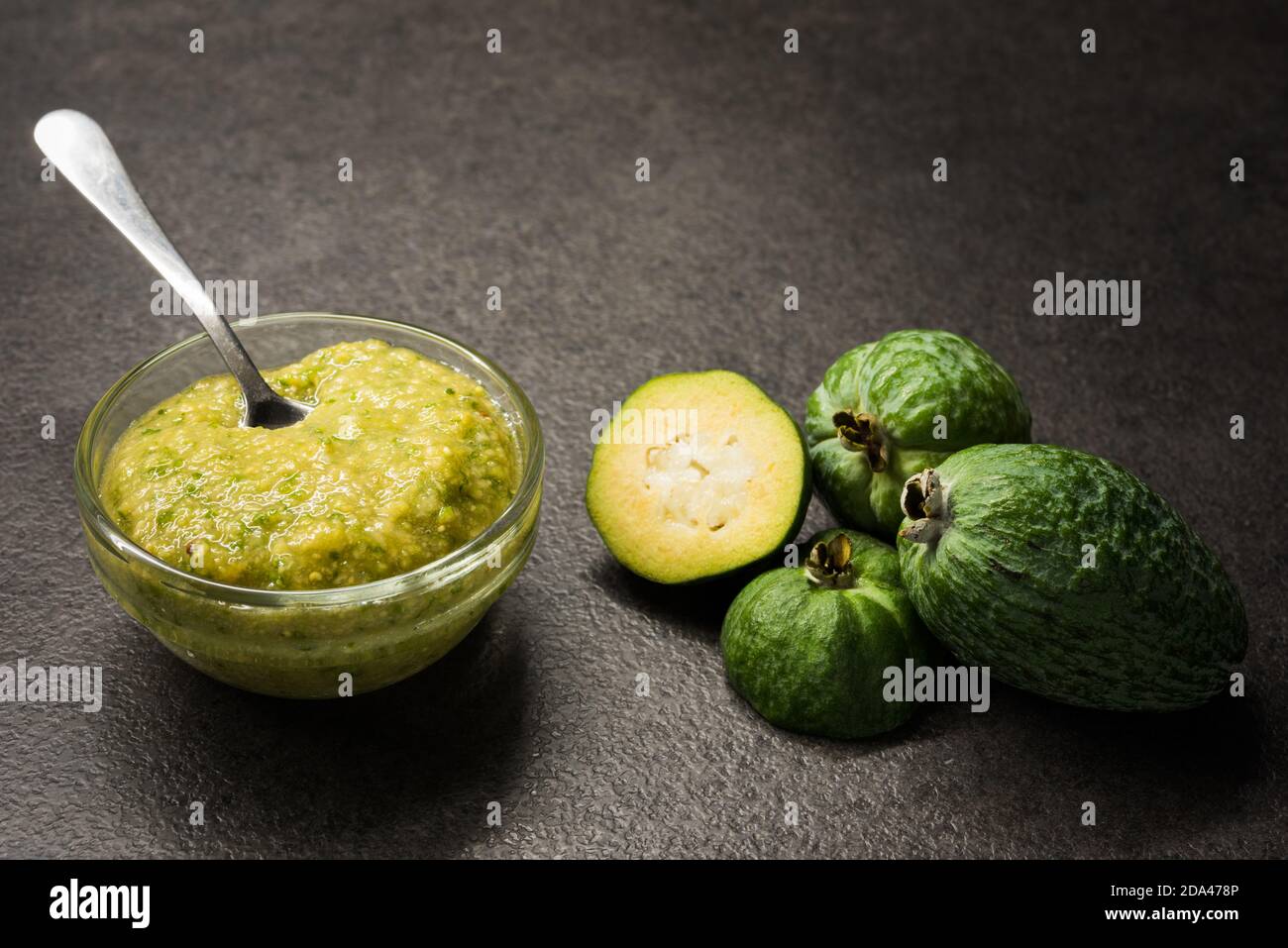 Green feijoa on a gray board on the table, next to feijoa jam. Healthy ...