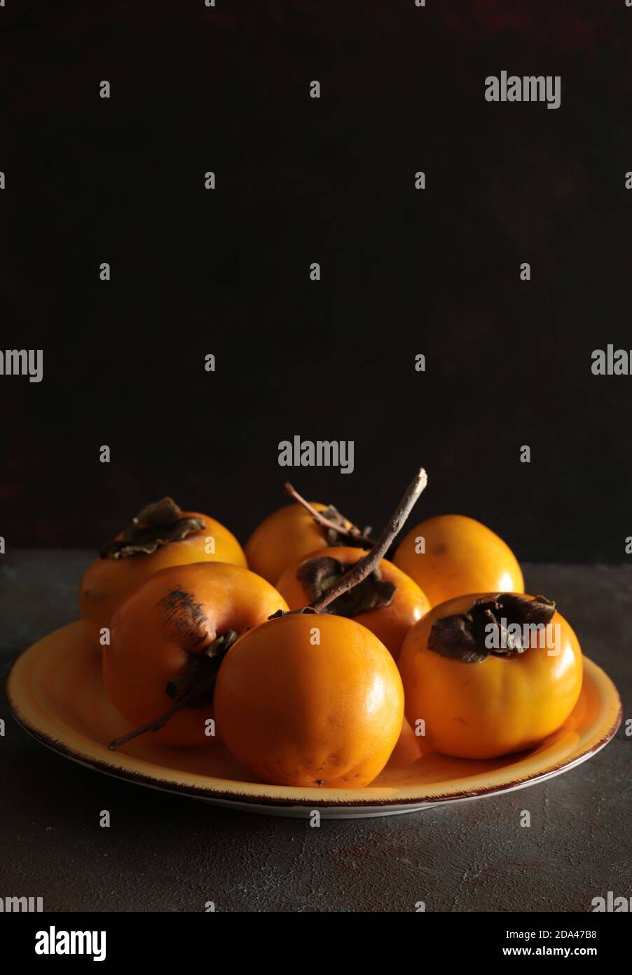 Group of fresh persimmons isolated on dark background. Selective focus ...