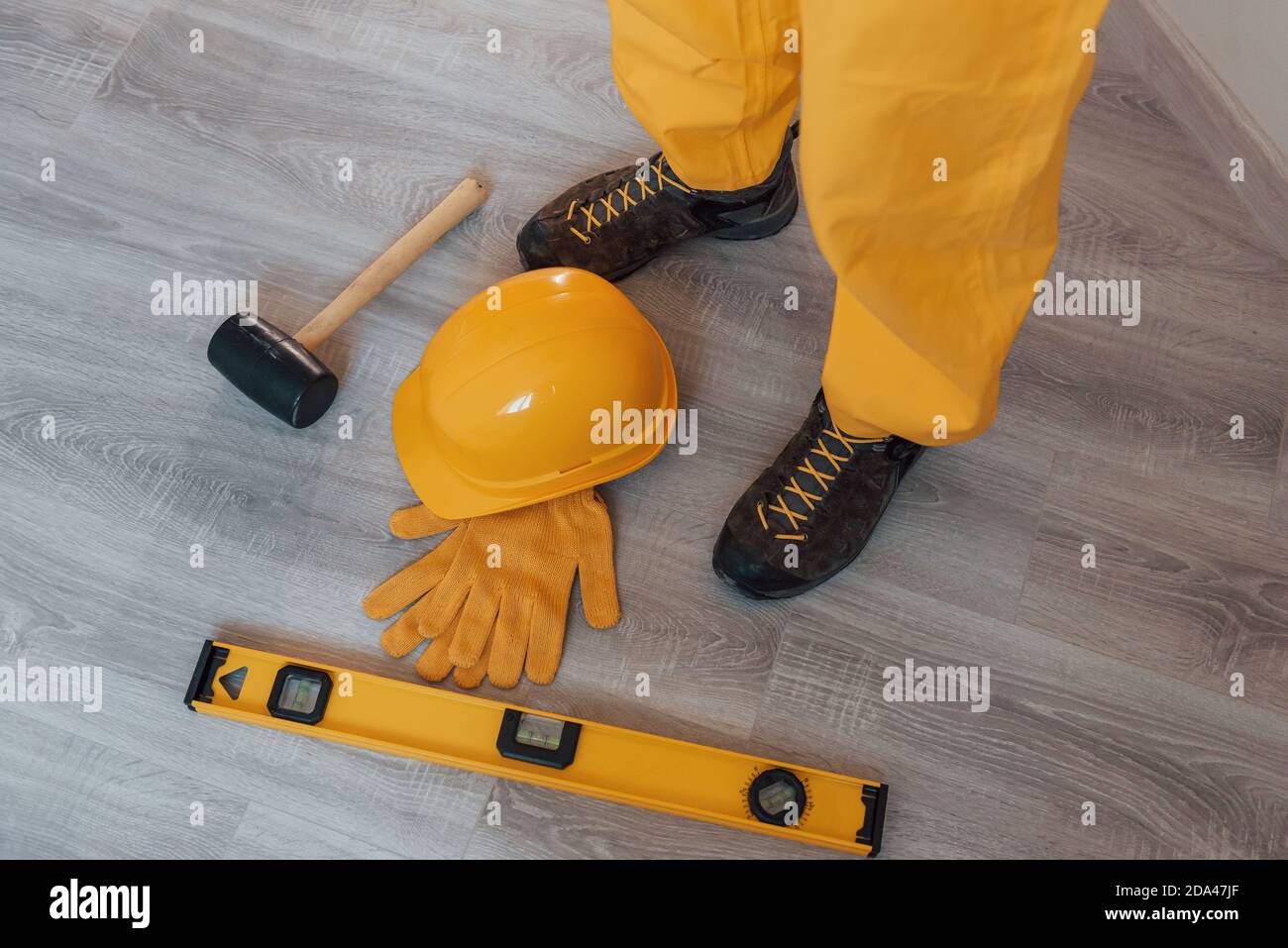 Tools on the floor. Handyman in yellow uniform standing indoors. House ...