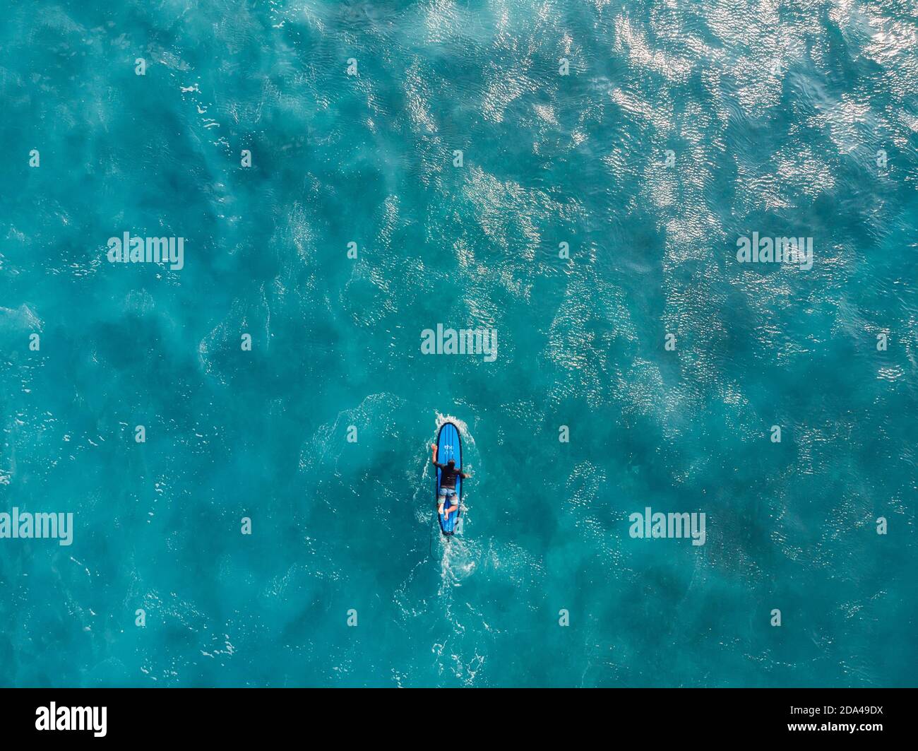 Aerial view of surfer on surfboard in blue ocean with foam. Top view ...