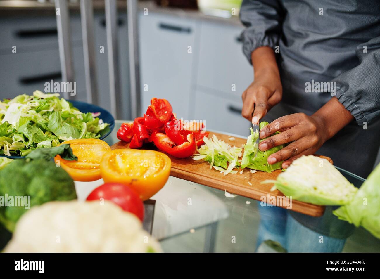 African american woman preparing healthy food at home kitchen. She cuts ...