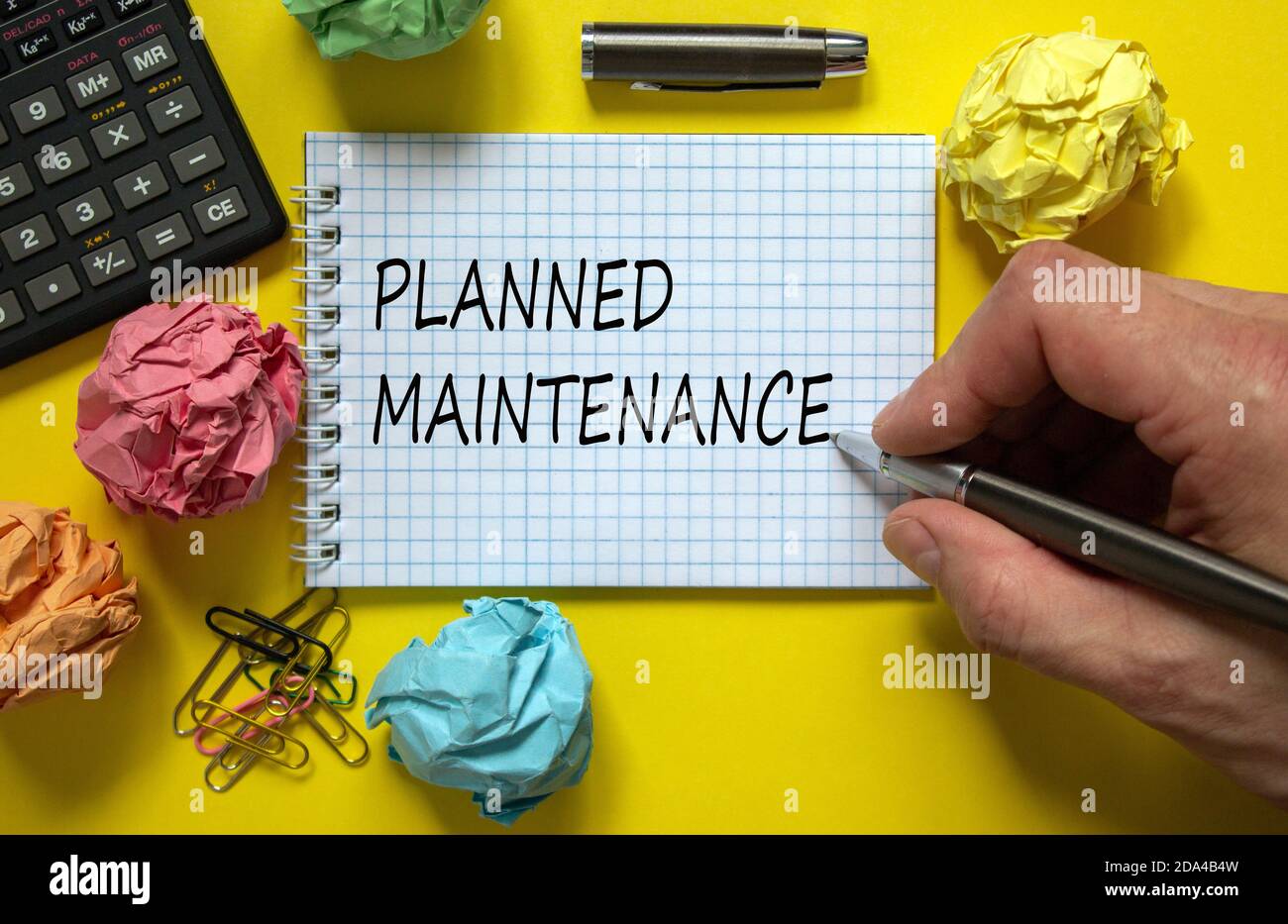 Businessmans hand writing 'planned maintenance' on white note ...