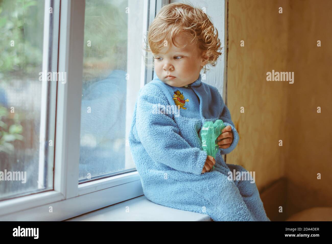 a little boy is sitting by the window Stock Photo - Alamy