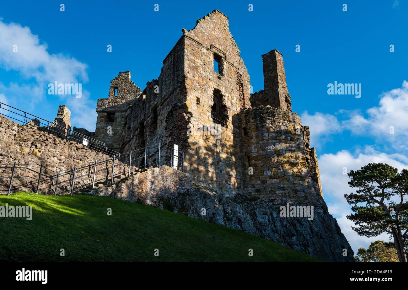 High ruined walls of Medieval Dirleton Castle on sunny day with blue ...