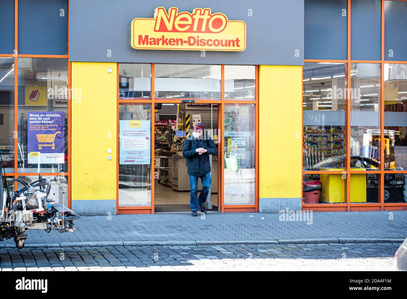 Spring 2020. Frankfurt, Germany. Grocery storefront with man walking ...