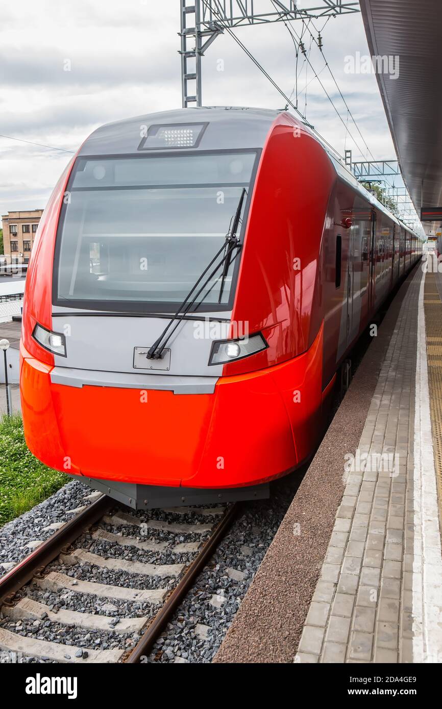 Modern red train approaching the train station Stock Photo - Alamy