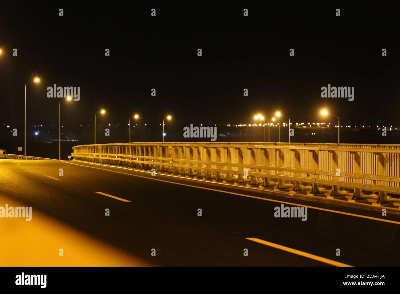 An empty night street lit by lanterns, some city lights in the distance ...