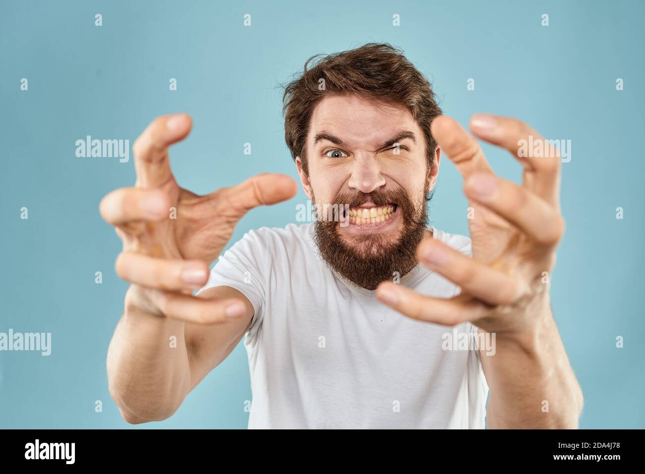 Bearded man in white T-shirt emotions gestures with hands displeased ...