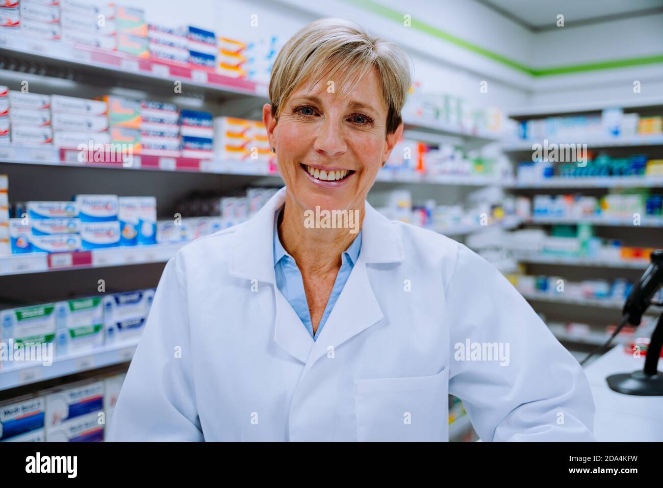 Portrait of caucasian woman pharmacist smiling in front of medication ...