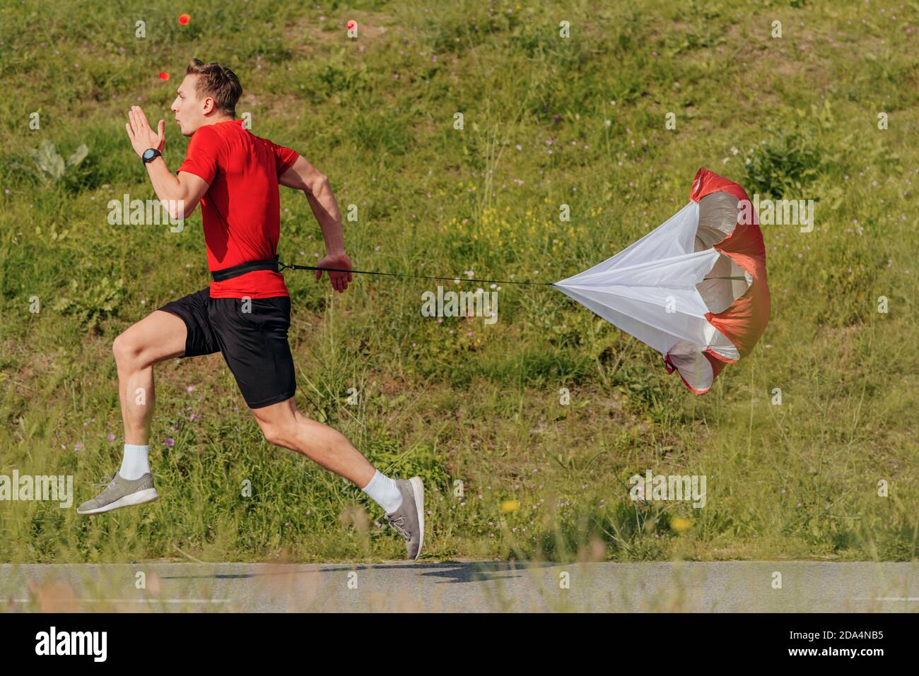 Side view of a strong man doing workout using resistance parachute ...