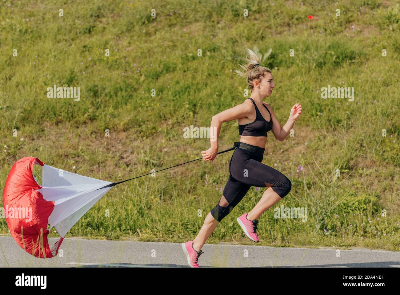 Side view of a young fitness woman running using red resistance ...