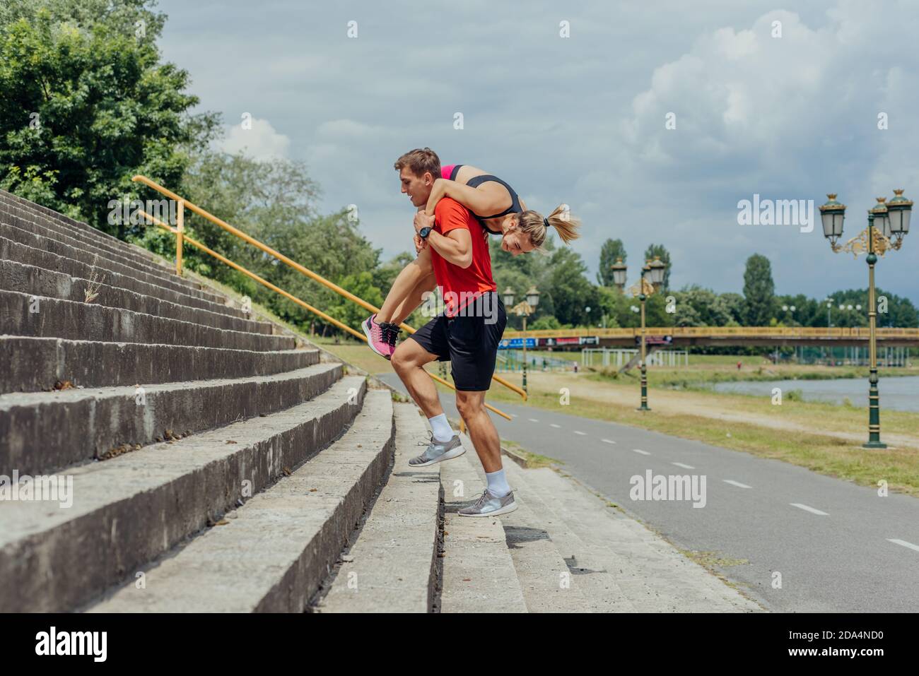 Male athlete carrying his female workout partner on his shoulders while ...