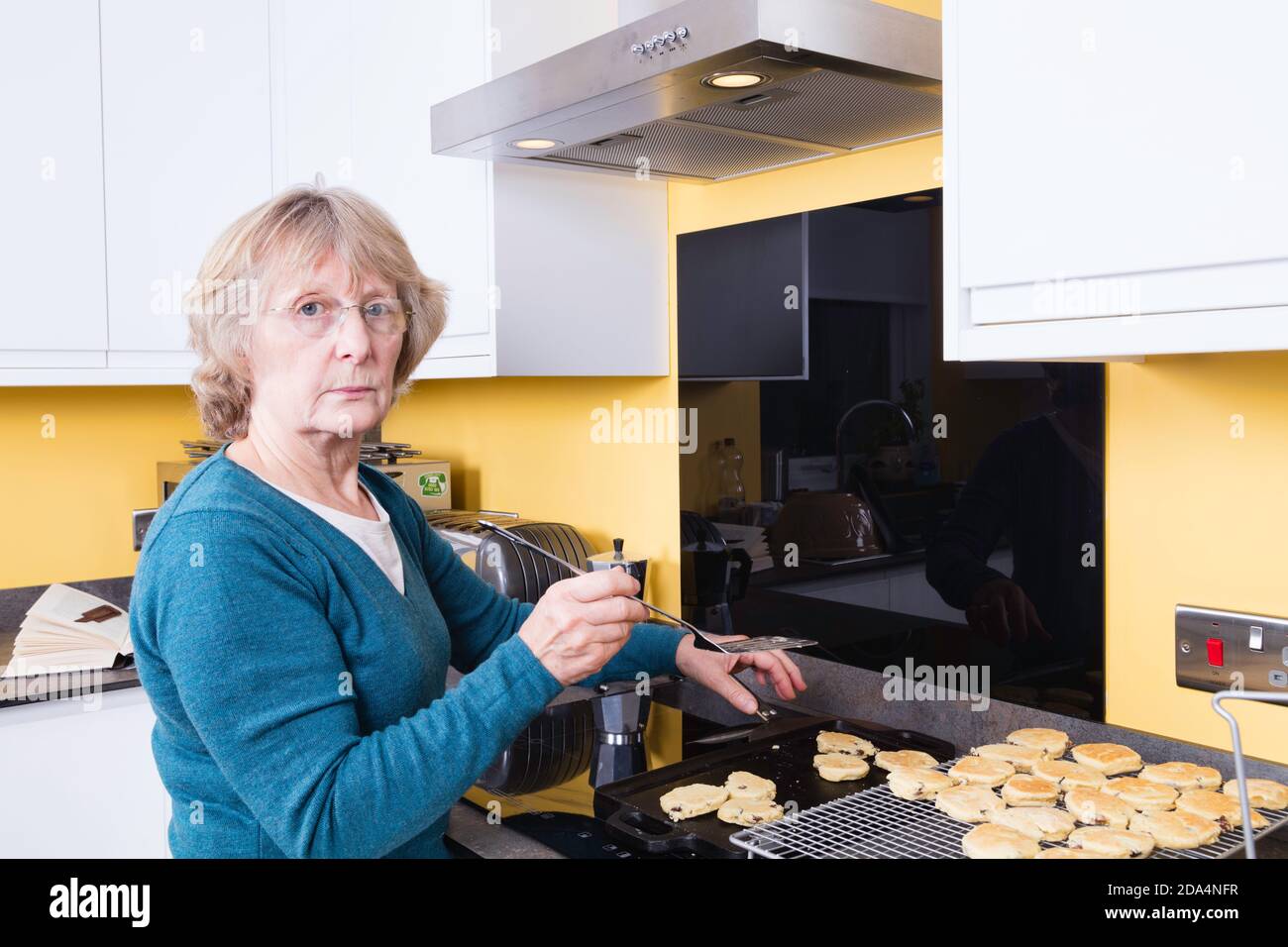 Lady in her late 60s baking Welsh cakes on a griddle in her kitchen ...