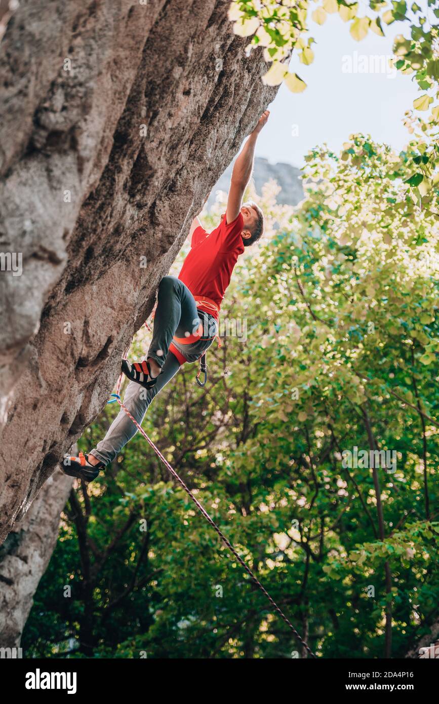 Strong happy male climber practicing climbing on rock wall Stock Photo ...