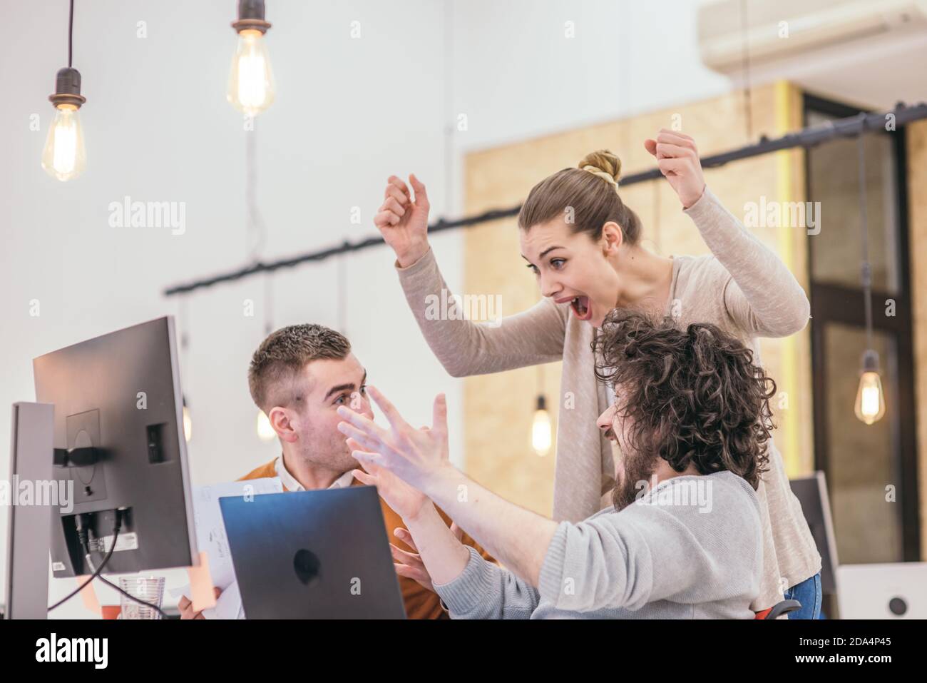 Happy surprise for the teammates. Coworkers cheering while looking at a ...