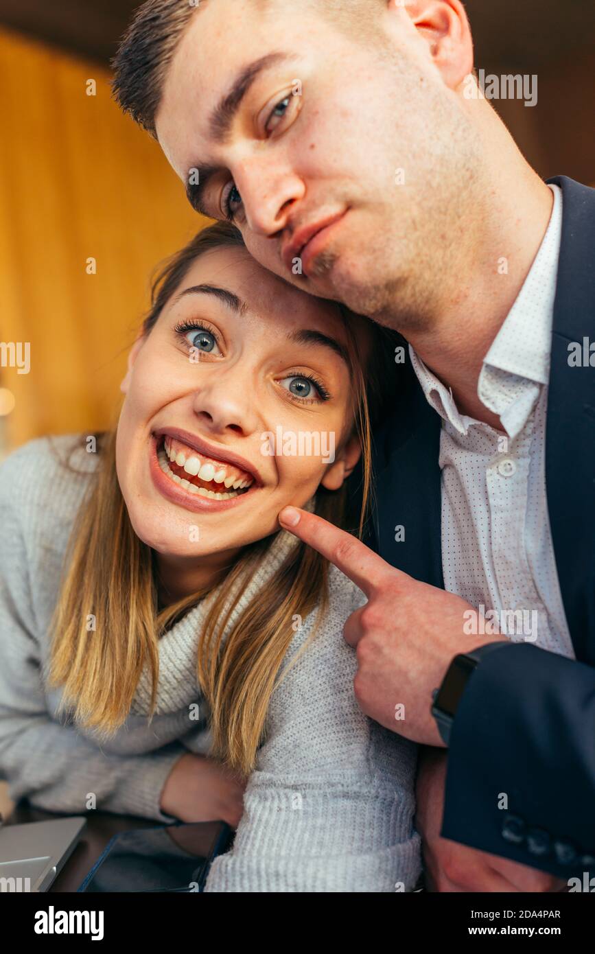 Couple having fun in a cafe ( coffee shop) while making crazy faces and ...