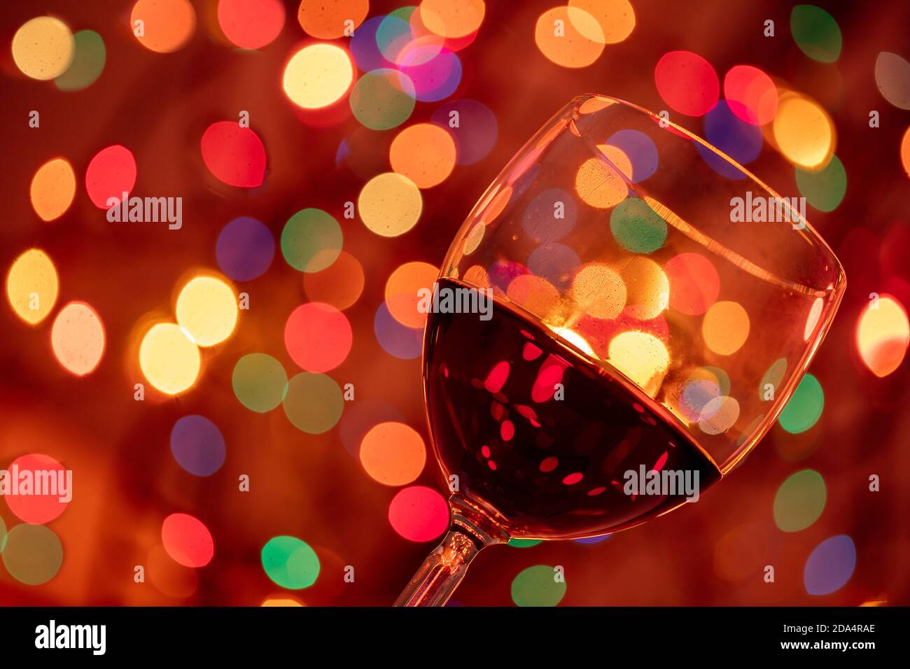 Red wine glass against christmas lights colorful bokeh background ...