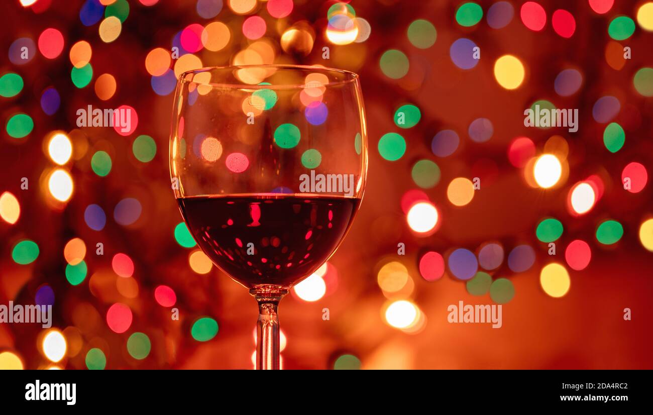 Red wine glass against christmas lights colorful bokeh background ...