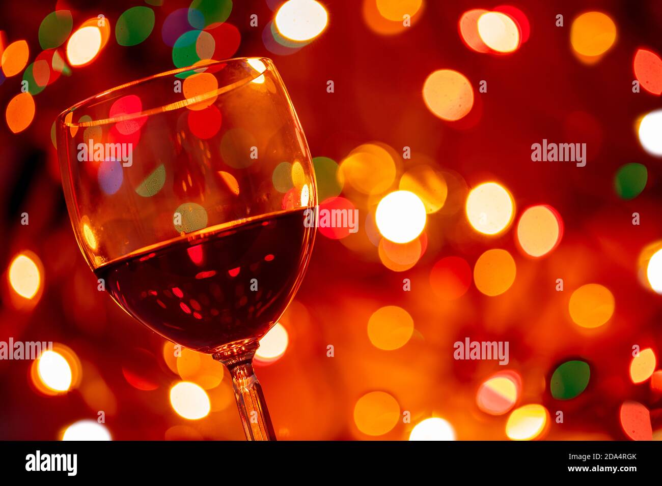 Red wine glass against christmas lights colorful bokeh background ...