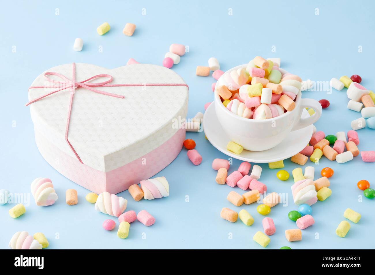 Closeup of a cup filled with marshmallows and a heart-shaped box ...