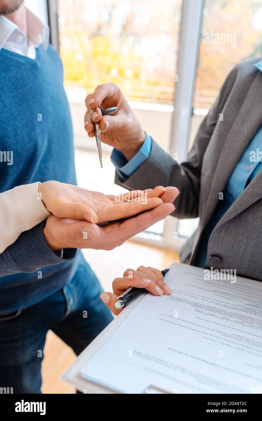 Realtor woman giving house keys to couple, closeup Stock Photo - Alamy