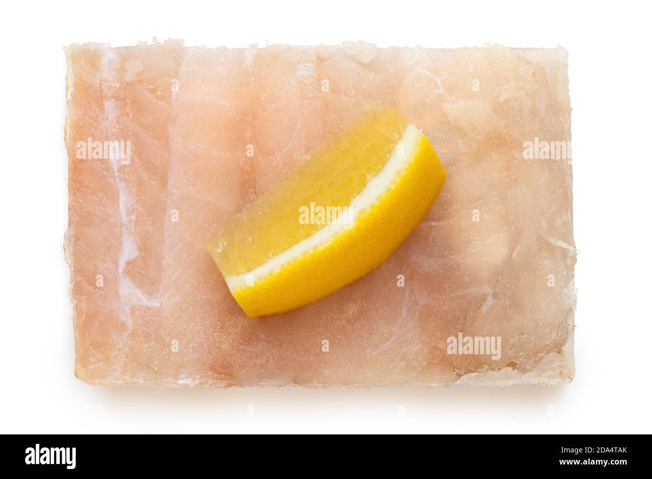 Quick frozen fish fillet block with a lemon wedge isolated on white ...