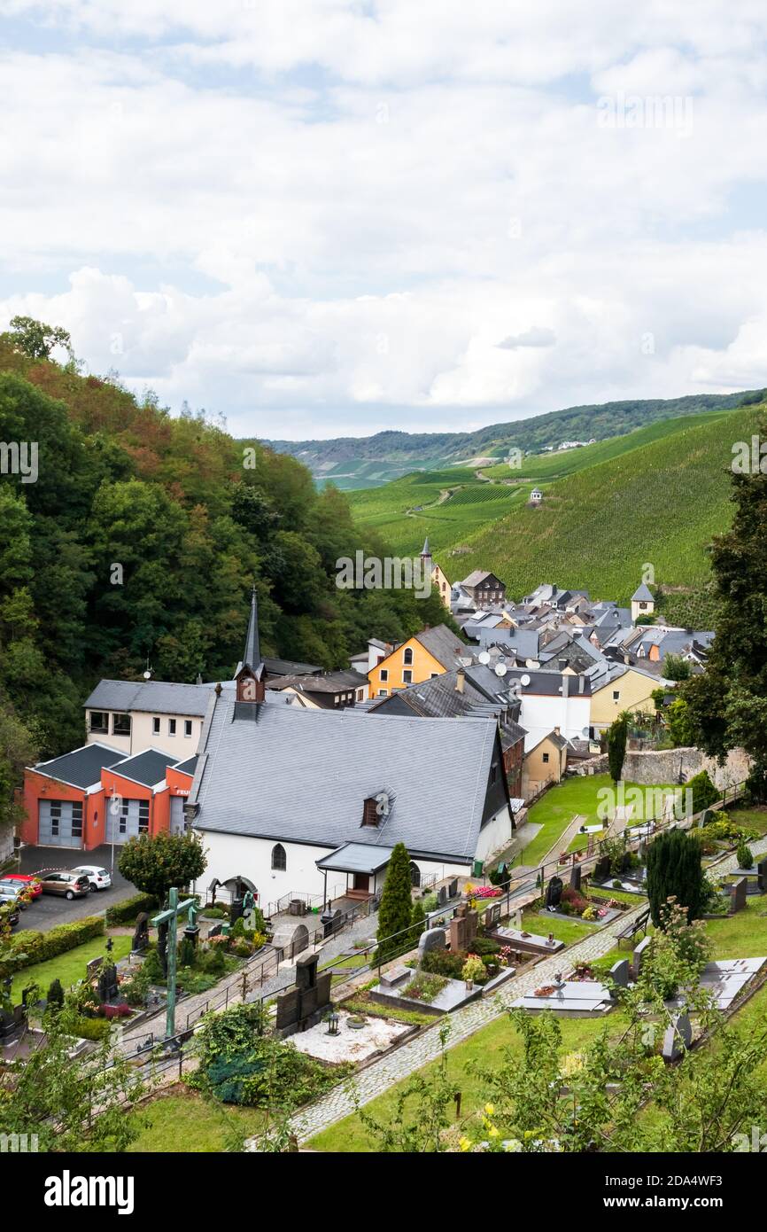 Cemetery and houses in a small village surrounded by trees and hills ...