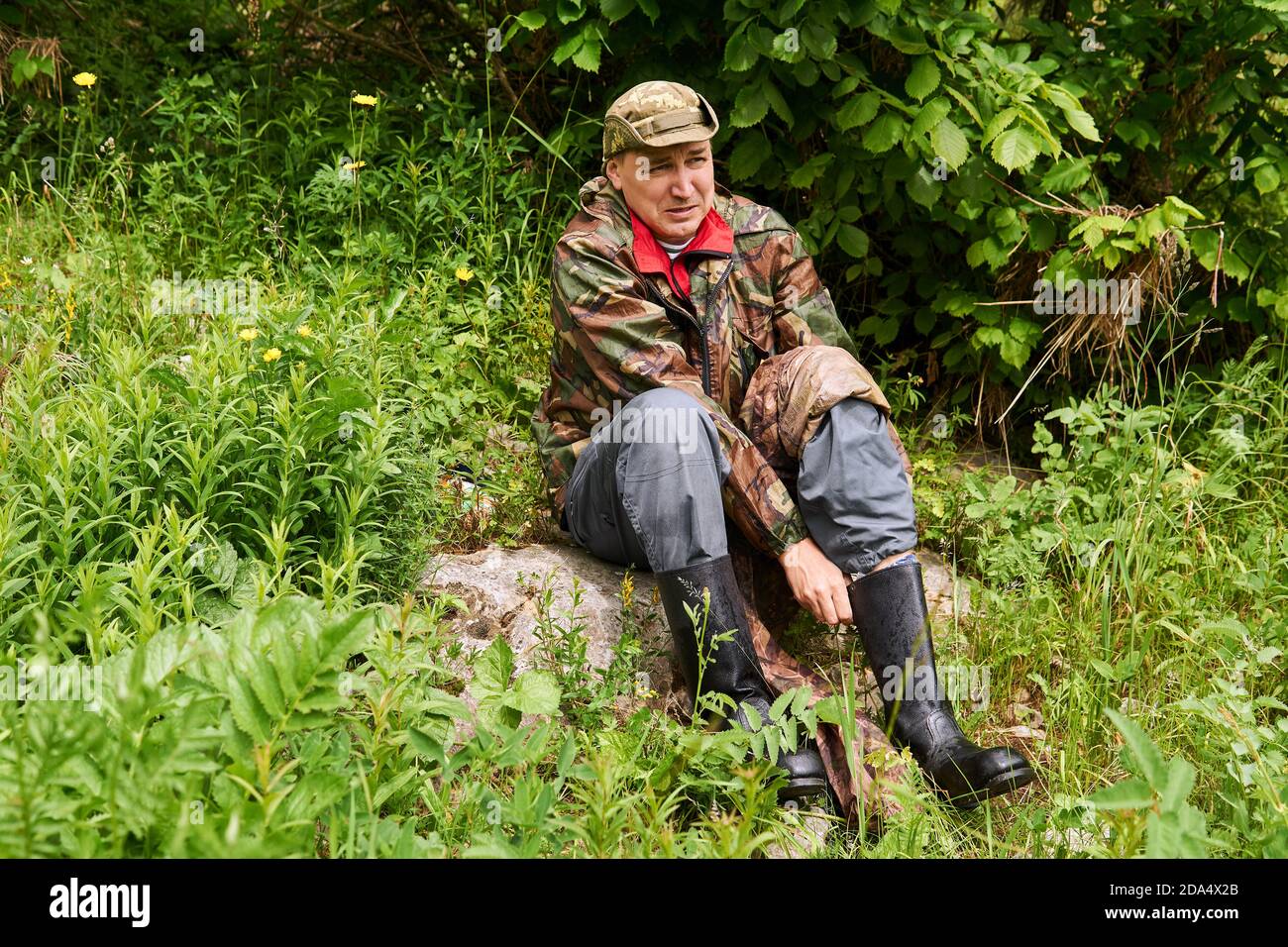 man traveler dressed in military style, changing boots using a ...