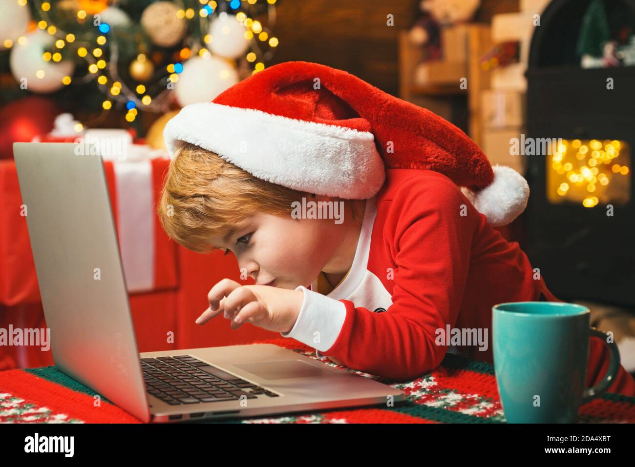 Christmas little boy typing letter to Santa Claus on a computer at home ...