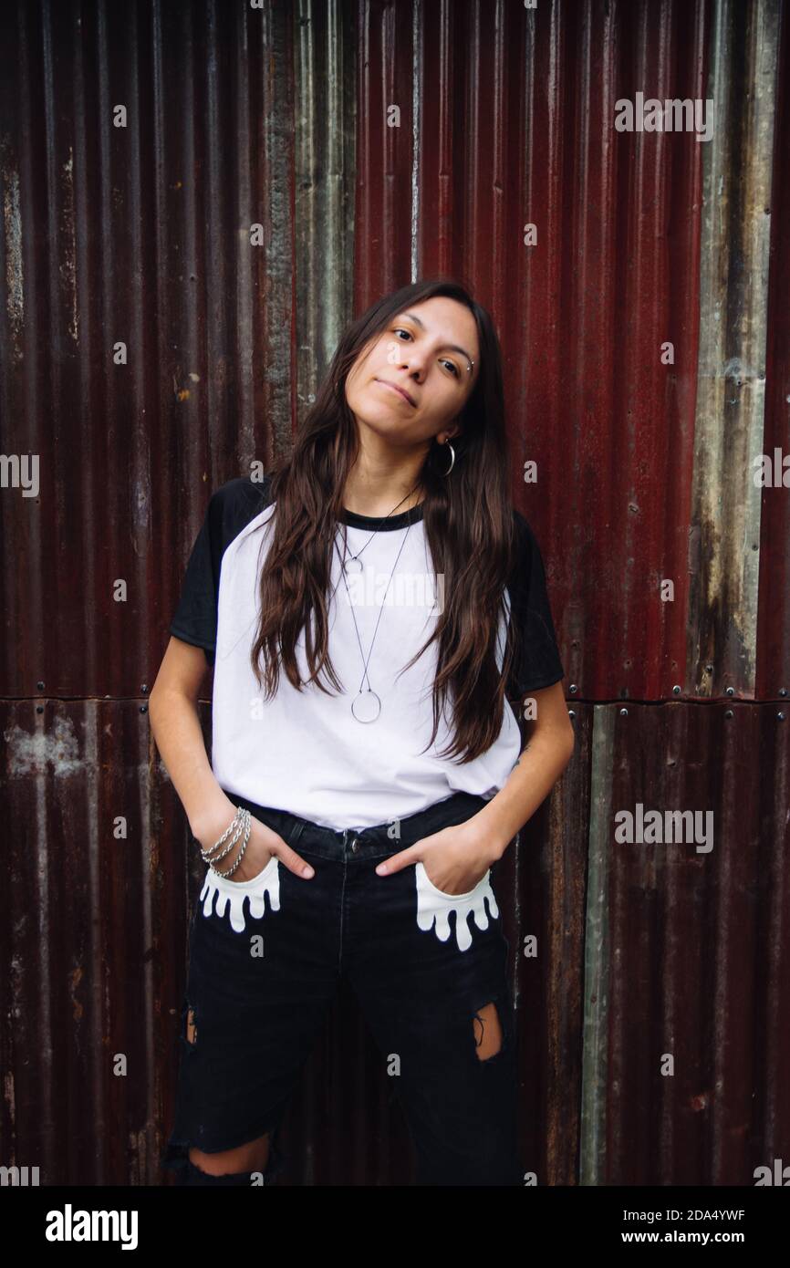Vertical shot of a cool hip young female posing in front of a rustic ...