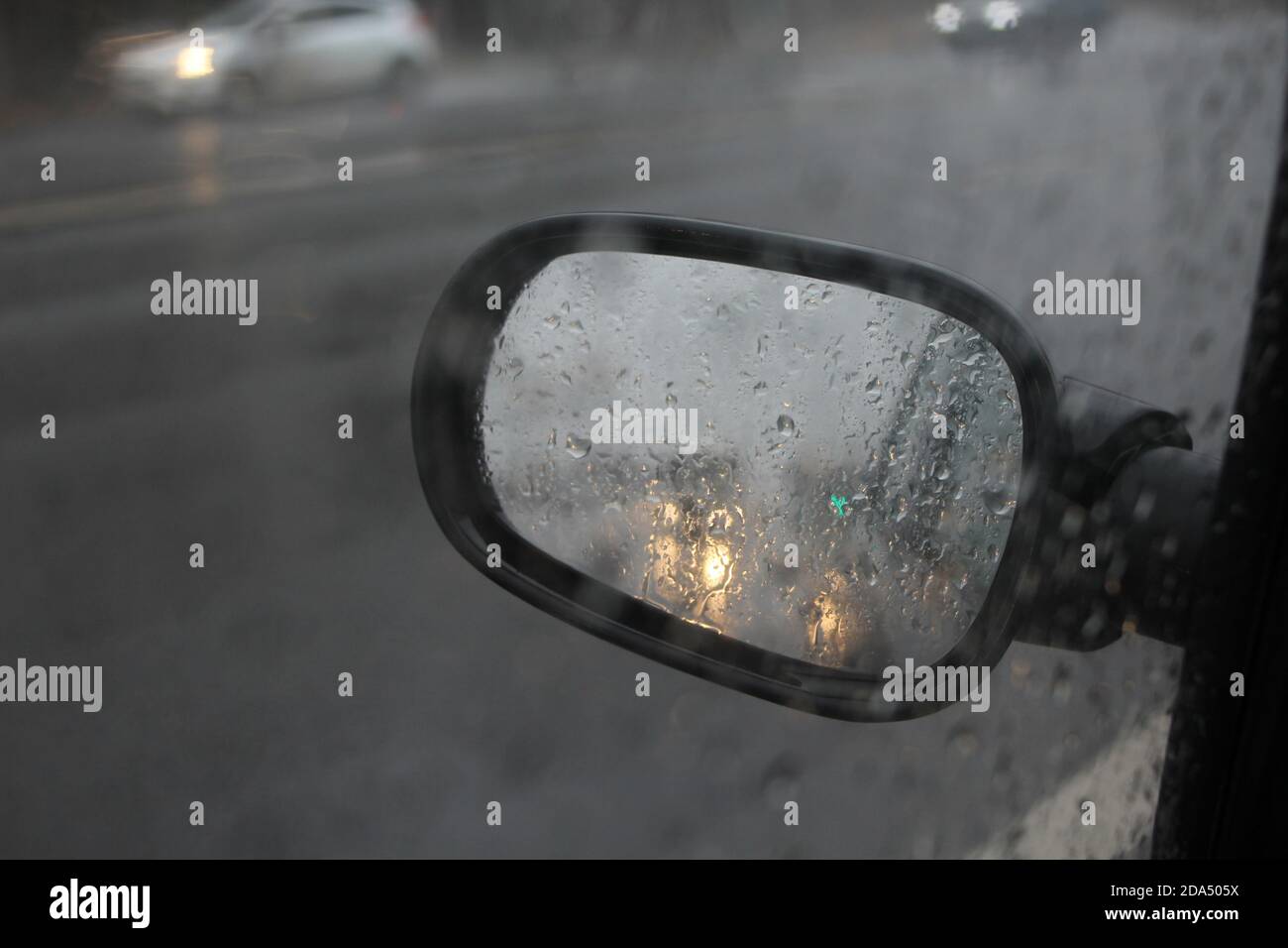 Detail of rear-view wet mirror in the rainy weather. Highway and cars ...