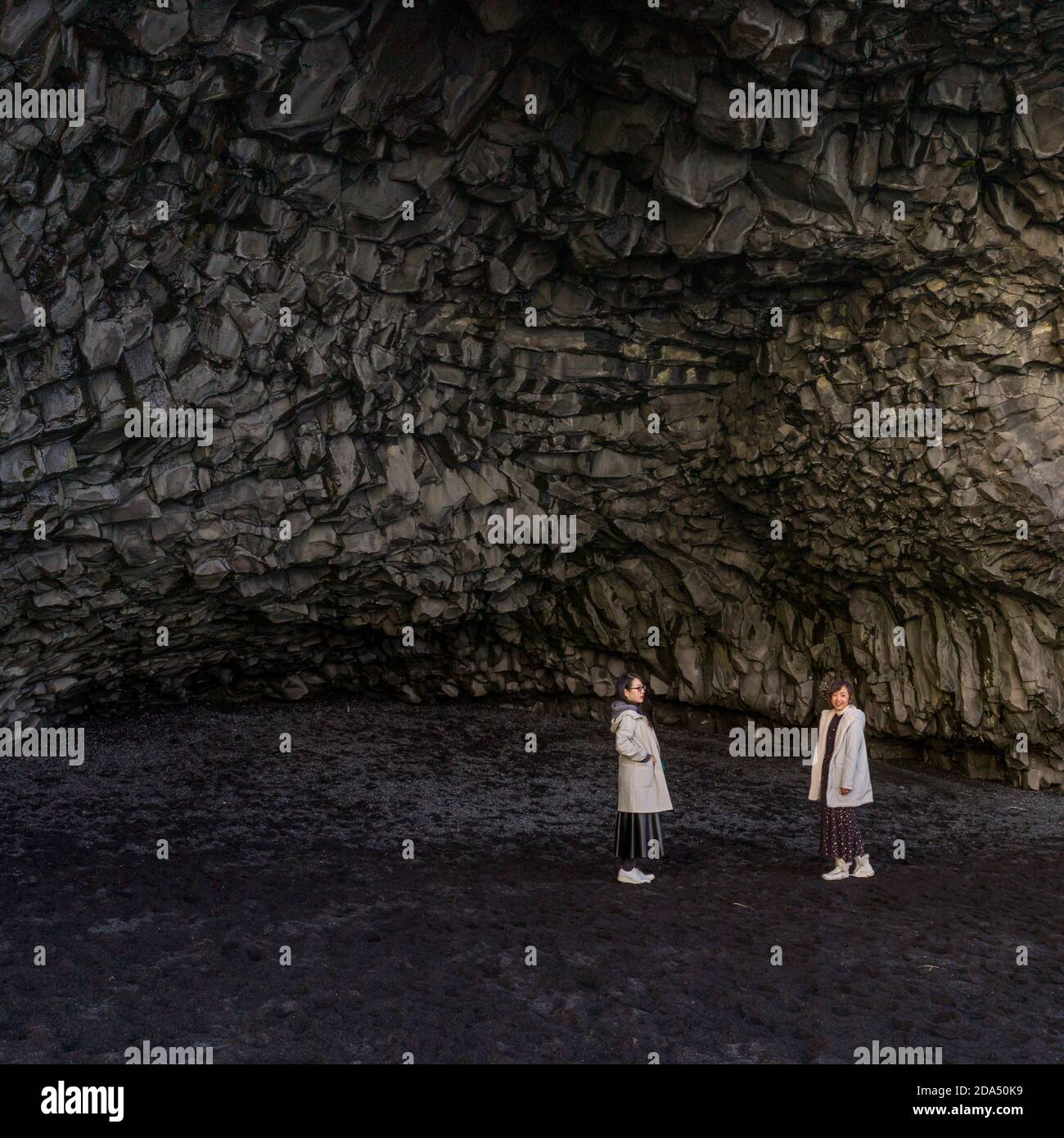 Two women standing in cave of basalt rocks, Reynisfjara Black Sand ...