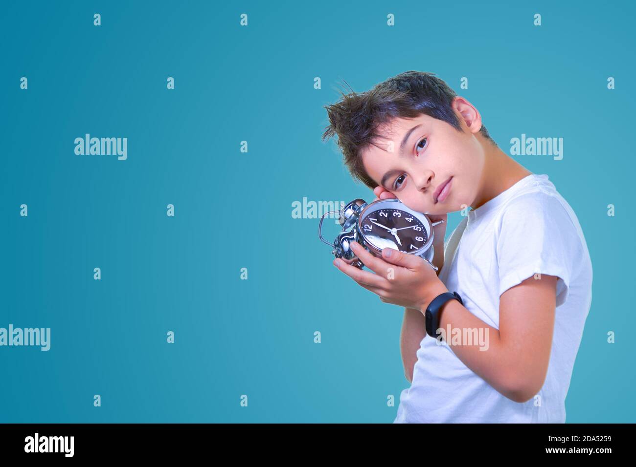 School boy with alarm clock in hands isolated on blue. Time to go Stock ...