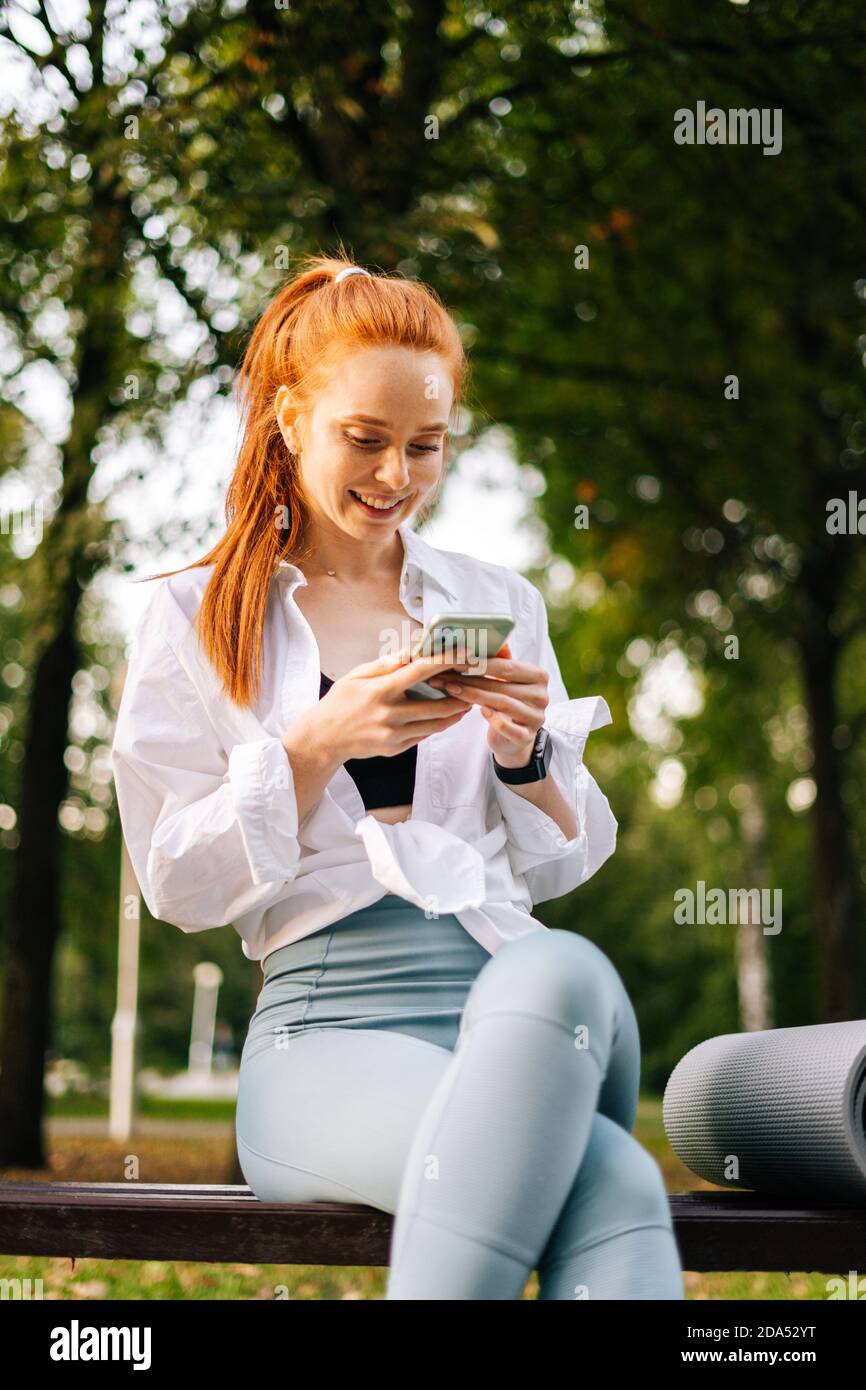 Low-angle shot of woman browsing internet on smartphone. Portrait of ...