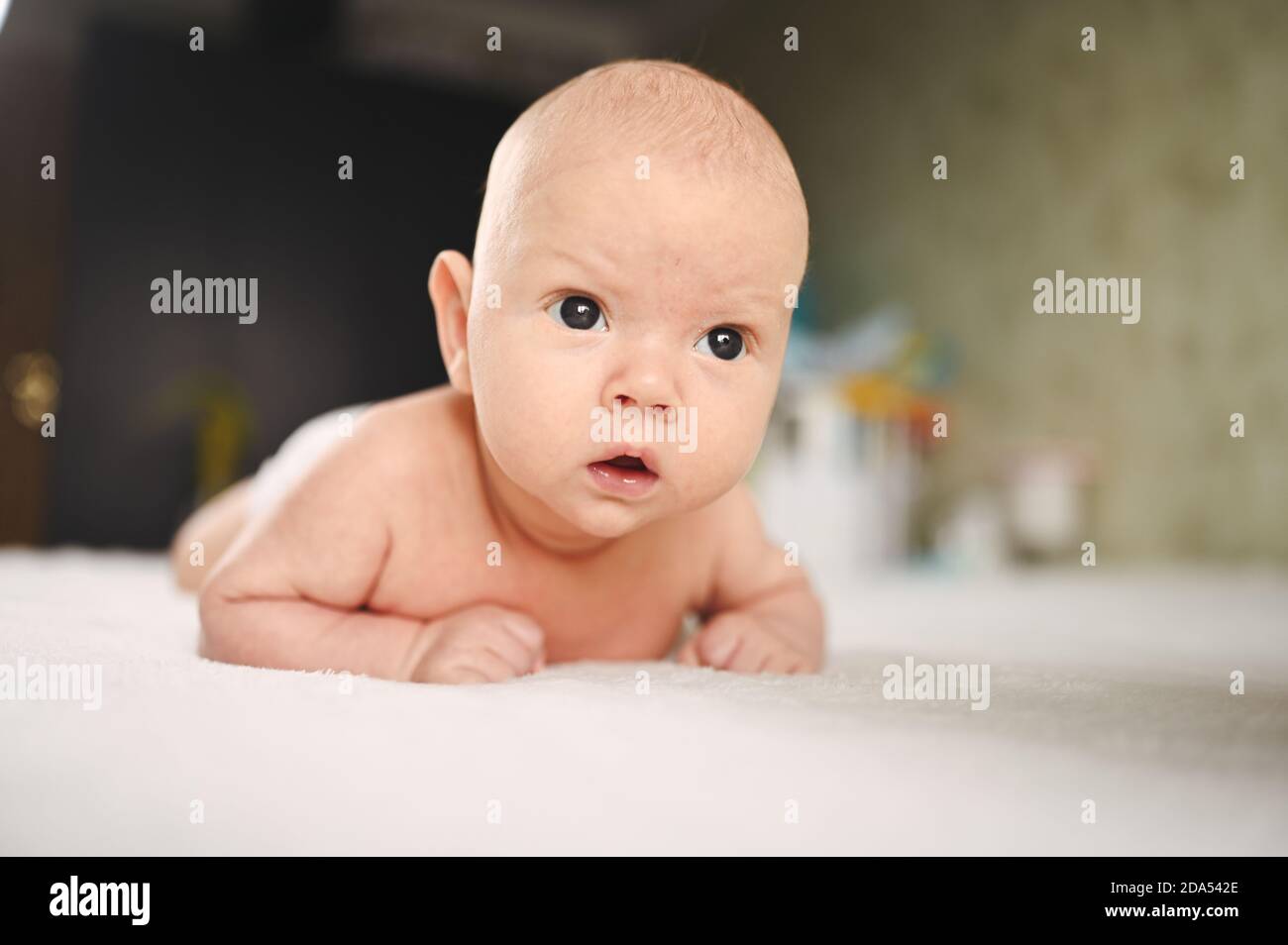 Cute emotional funny newborn boy laying on bed. Baby facial expressions ...