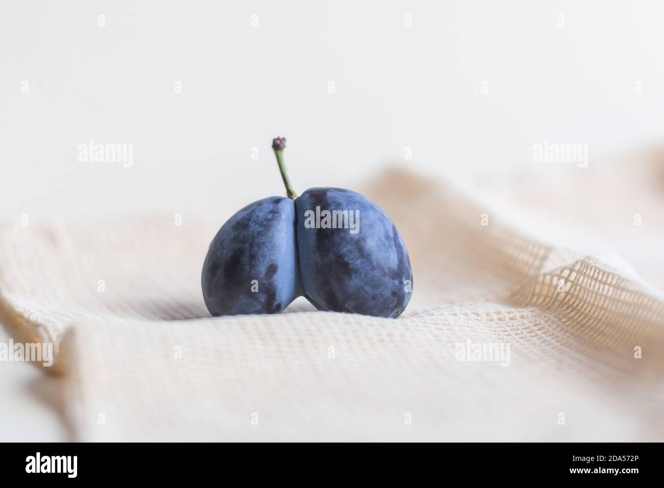 Ugly organic blue double plums heart-shaped on a white background. The ...