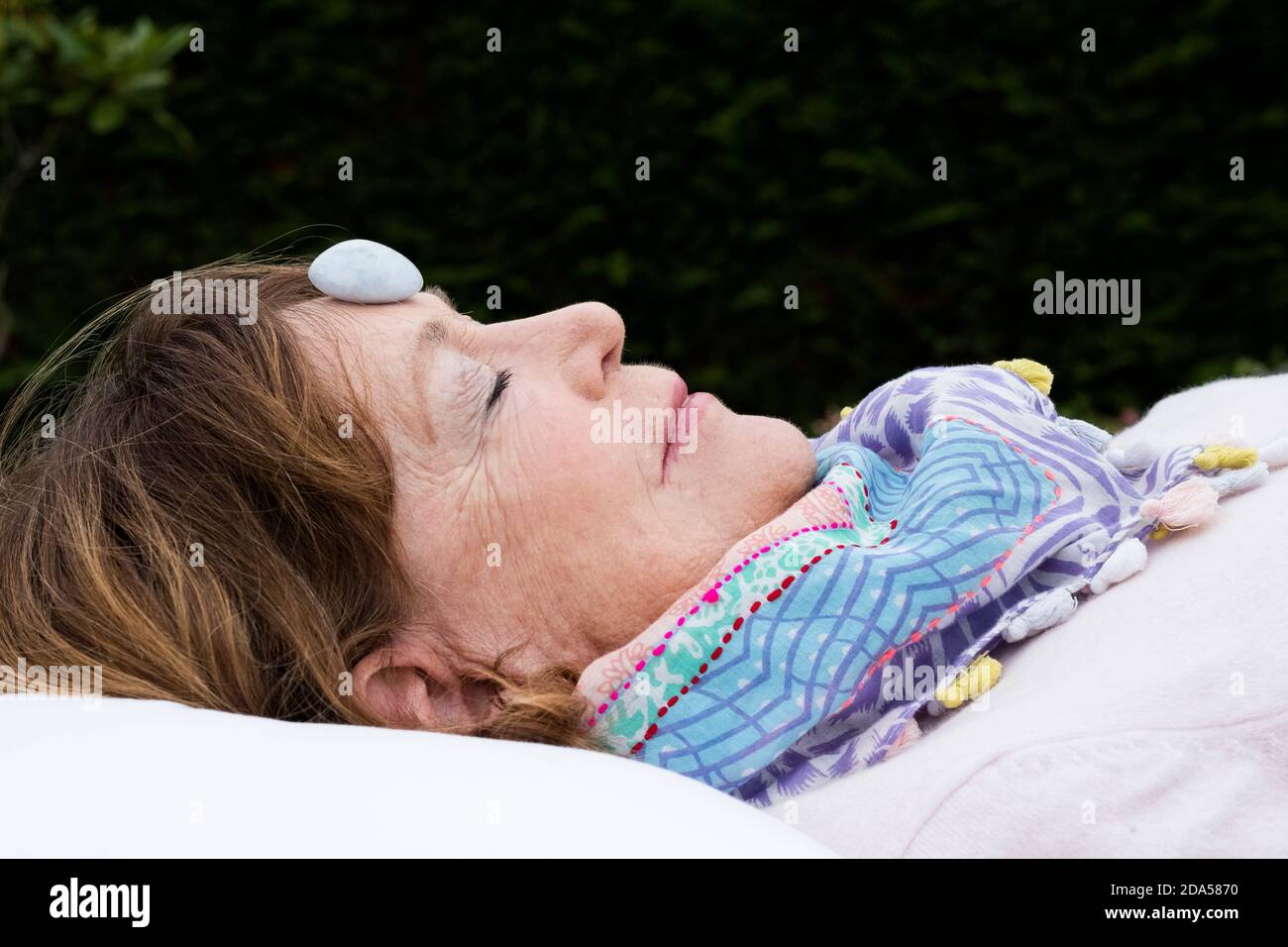 Woman with stone on her forehead during alternative therapy session in ...