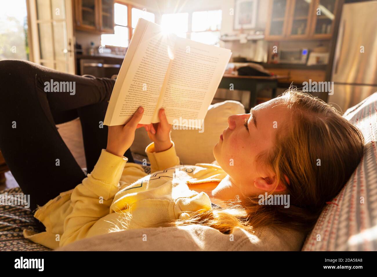 teenage girl reading book at home in early morning light Stock Photo ...
