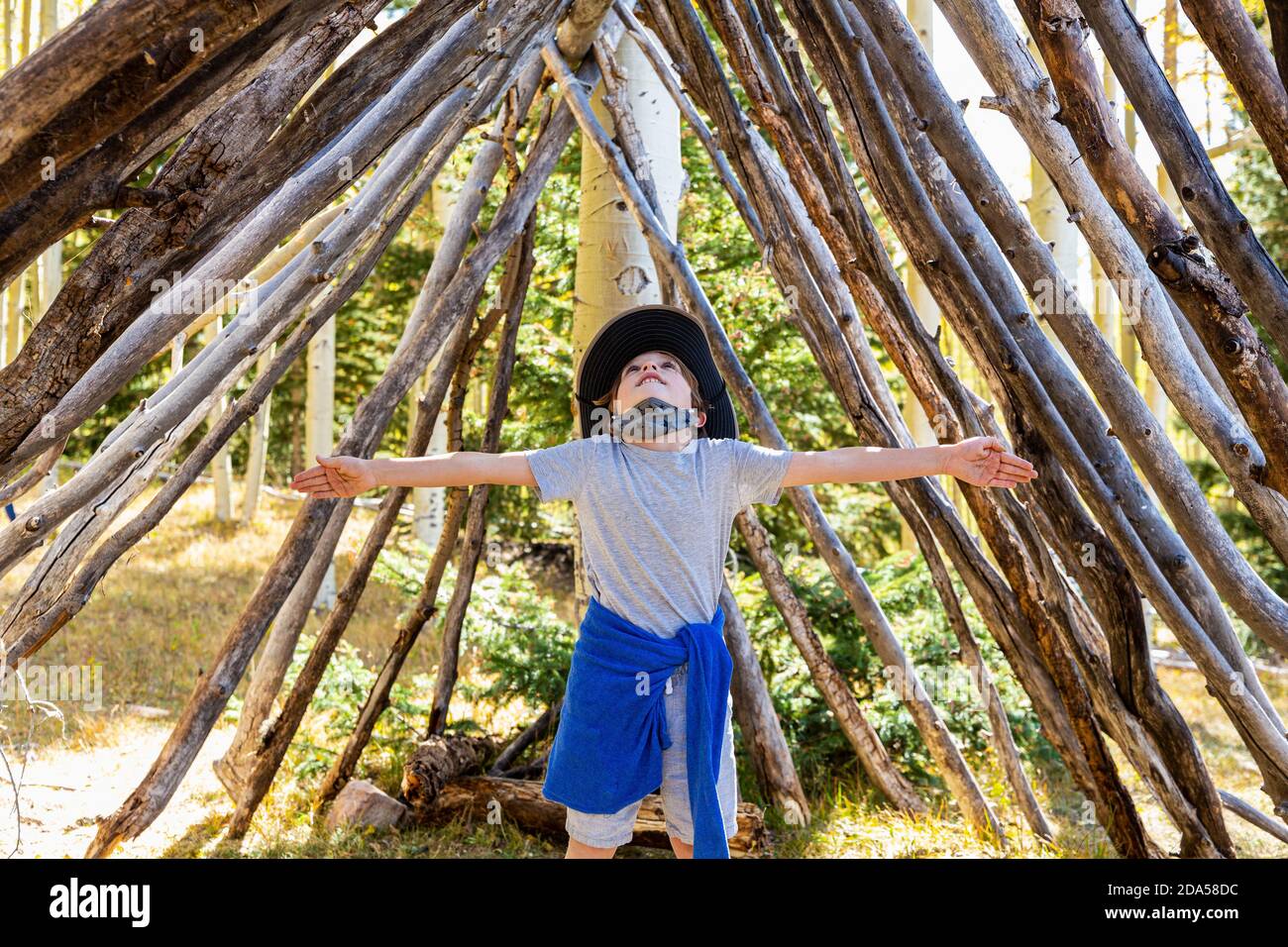 Young boy looking up, standing in a tunnel made of tree logs Stock ...