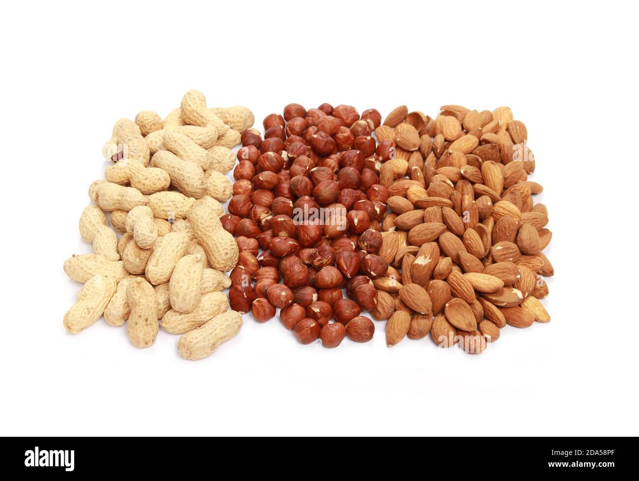 Closeup of heap of peanuts, hazelnuts and almonds isolated on white ...